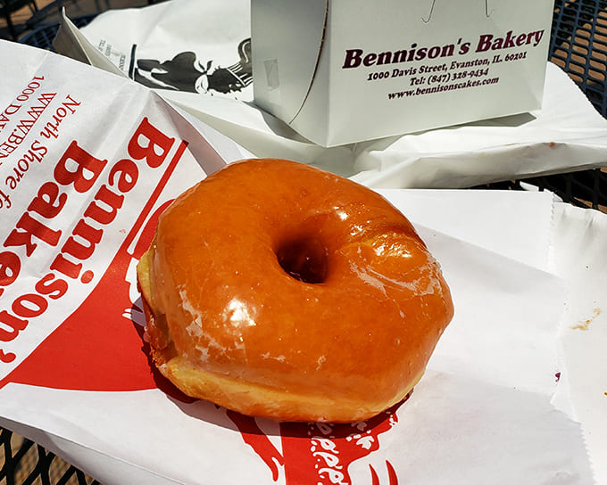 A single glazed donut sits in perfect solitude, its honey-colored glaze catching the light like nature's own food photography lighting.