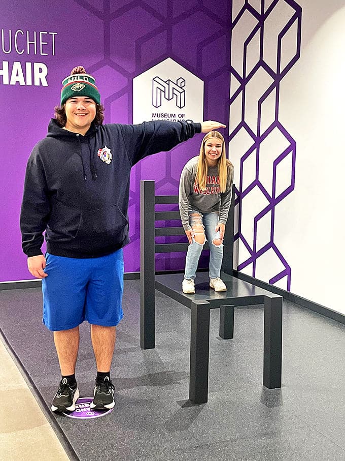 The classic Beuchet Chair illusion makes normal-sized adults appear doll-sized through forced perspective. Size is just a matter of opinion here!