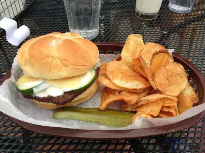 A burger that would make any pickle enthusiast weak at the knees, served with house-made chips that crunch louder than your excitement.