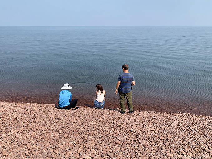 The glassy calm of Lake Superior creates a perfect mirror for contemplation, framed by a shoreline of rosy rhyolite pebbles.