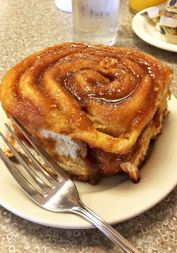 The legendary caramel roll in all its glory &ndash; a golden-brown spiral of joy glistening with buttery caramel that pools around the edges.