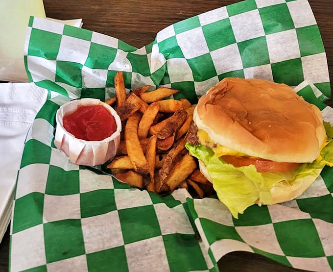 Cheeseburger with fries: Perfection on a green checkered paper &ndash; a juicy burger alongside golden fries that demand to be savored slowly.