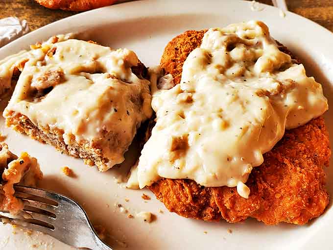 The legendary chicken fried steak arrives like edible artwork &ndash; golden-crisp exterior, tender meat within, all swimming beneath a creamy river of country gravy.