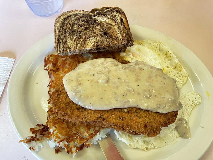Country fried steak smothered in peppery gravy alongside sunny-side up eggs and hash browns – breakfast doesn't get more satisfying than this.