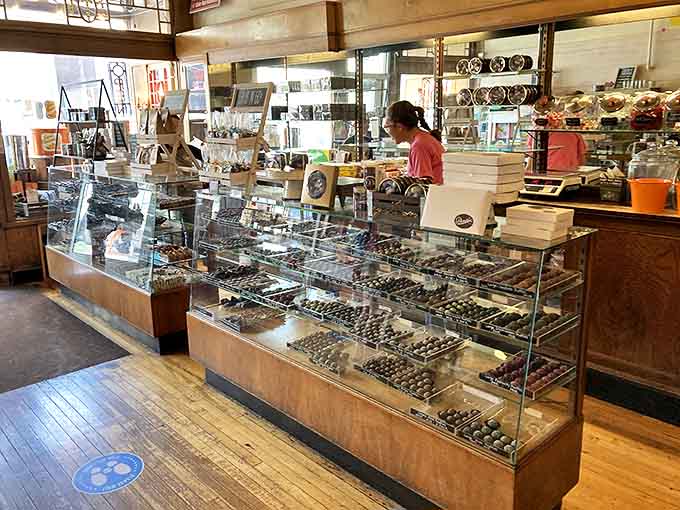 The display case gleams with chocolates arranged like edible jewelry, each piece practically begging you to abandon your diet immediately.