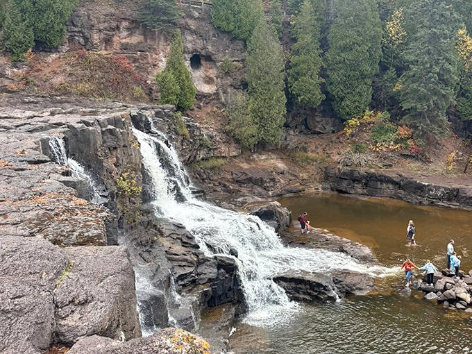 Visitors explore the rocky shoreline, where generations have perched to dangle feet in the cool waters after hiking the loop trail.