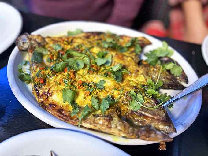 The Grilled Sea Bream arrives like edible art, its crispy skin giving way to tender flesh beneath a shower of fresh herbs.