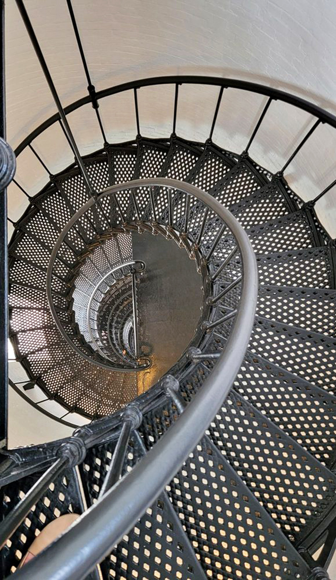 The dizzying spiral staircase winds like a nautical DNA strand. Each step tells stories of keepers past who climbed these same iron treads.