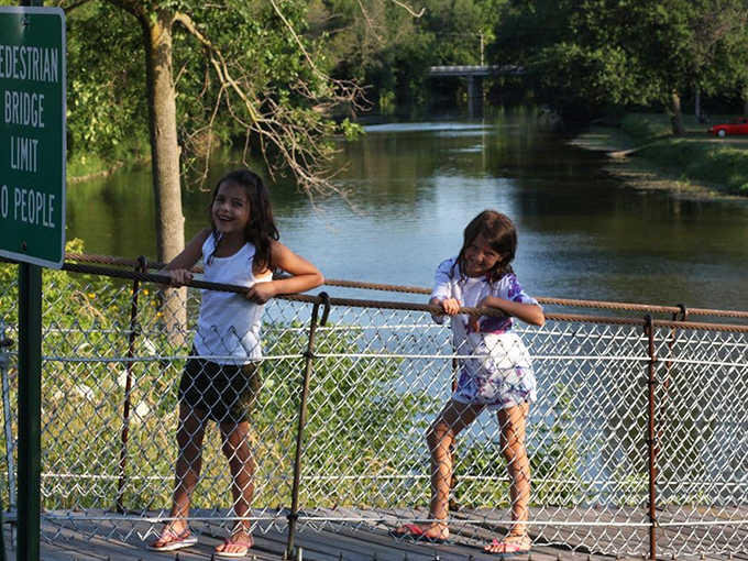 Young explorers discover the thrill of controlled movement, their giggles echoing across the water as the bridge responds to their steps.