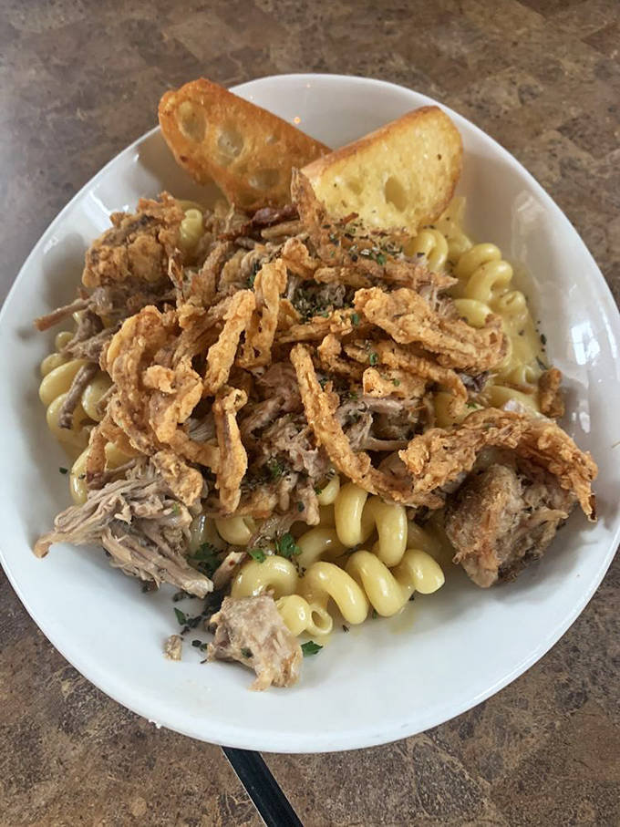 Mac and cheese that deserves its own fan club. Tender pasta swimming in creamy cheese sauce, topped with pulled pork and crispy bits. Comfort food nirvana.