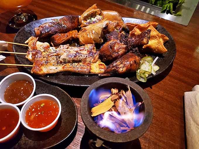 The legendary Pu Pu Platter arrives with dramatic flair—skewers, spring rolls, and wings surrounding a flickering flame that adds theatrical dining magic.