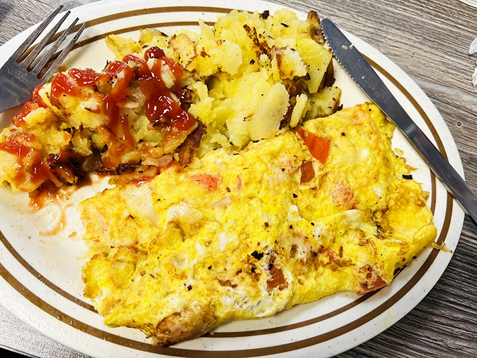 A perfectly executed omelet mission &ndash; fluffy eggs stuffed with savory fillings, accompanied by crispy potatoes that deserve their own medal of honor.
