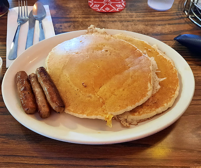 Golden pancakes with perfect crispy edges paired with sausage links that snap with each bite &ndash; breakfast nirvana on a simple white plate.