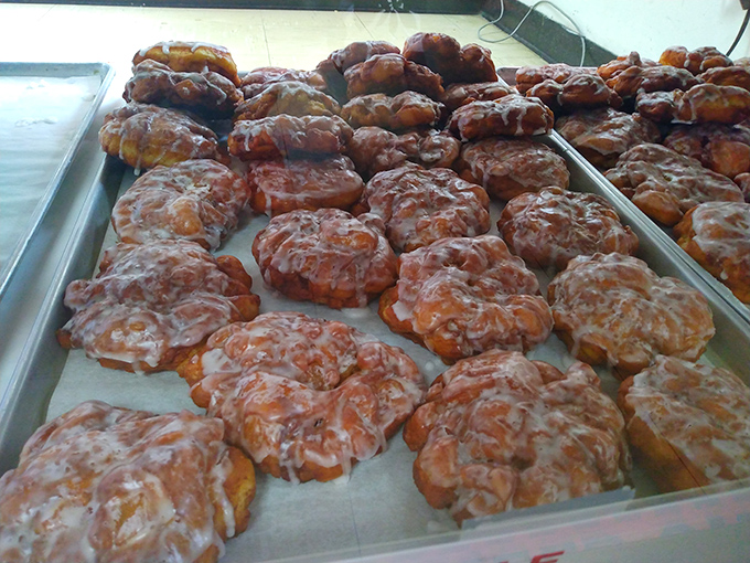 Trays of the shop's namesake apple fritters glisten under display lights, each irregular masterpiece promising chunks of apple in a cinnamon-spiced embrace.