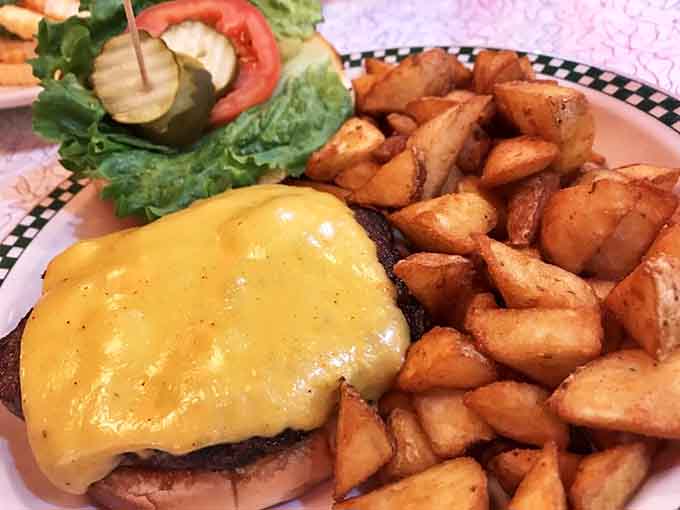 This isn't just a burger &ndash; it's edible architecture with melted cheese cascading down a hand-formed patty alongside golden potato bites.