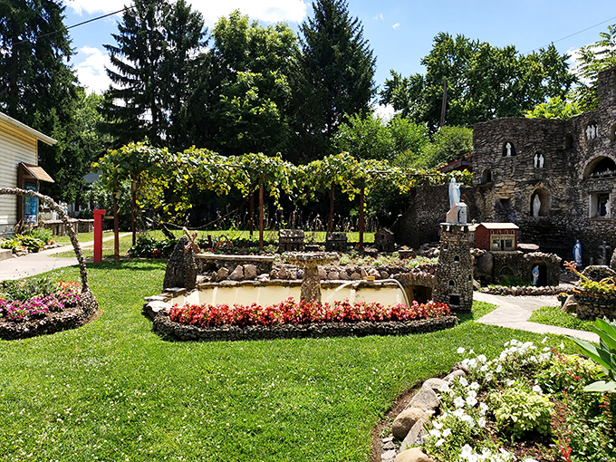 Miniature buildings line the garden paths, creating charming vignettes that make visitors feel like giants wandering through a stone village.