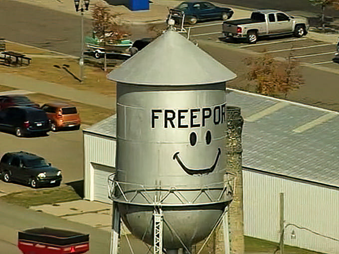 An aerial perspective reveals how the water tower stands sentinel over Freeport, its silver tank gleaming in the sunlight above the town.