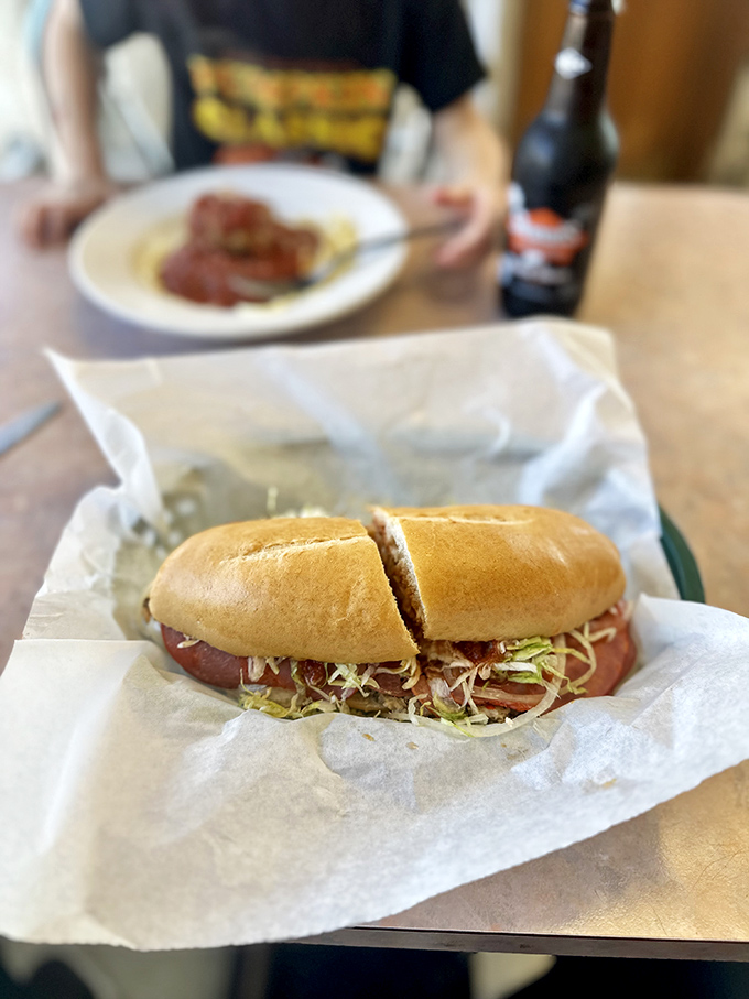 A perfectly constructed sandwich awaits its lucky recipient, nestled in paper with a side of crispy chips.