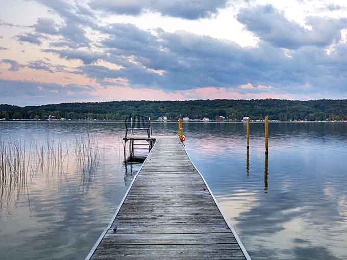 A wooden dock stretches into still waters at twilight &ndash; nature's front-row seat to the greatest show on earth, no tickets required.