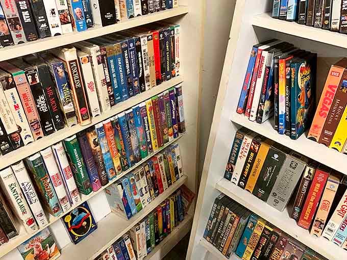 A nostalgic time capsule of VHS tapes lines the shelves, each plastic case holding movies from an era when "be kind, rewind" wasn't just a suggestion.