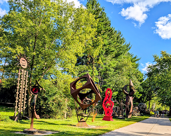A vibrant red musical note sculpture reaches skyward, its bold color a defiant shout against the quiet countryside backdrop.