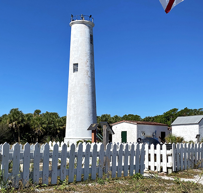 The lighthouse's stark white cylinder creates a dramatic contrast against Florida's famously blue skies and lush coastal vegetation.