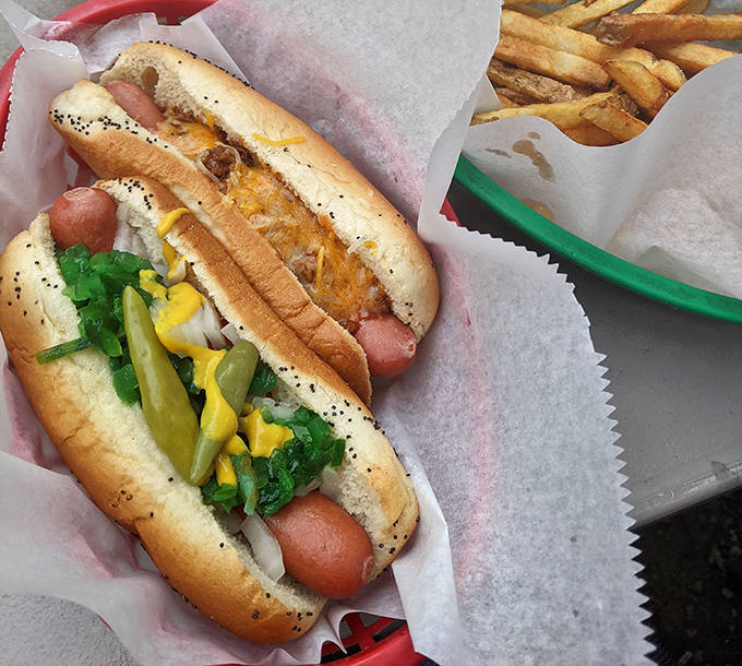 A close-up of hot dog perfection: Vienna beef nestled in a poppy seed bun, topped with mustard, relish, onion, tomato, pickle spear, and sport peppers.