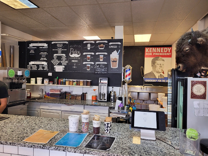 Behind this counter, magic happens daily. The Kennedy poster watches approvingly as sweet dreams are crafted for the masses.