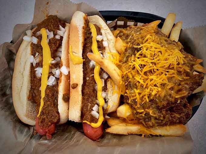 Chili, mustard, onions, and cheese create a symphony of flavors atop these dogs, with crispy fries playing backup.