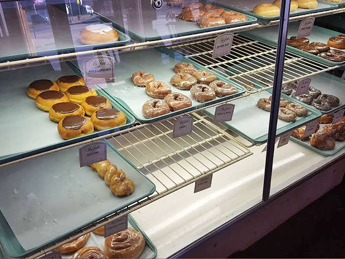 The display case presents a museum-worthy collection of pastries, each one handcrafted with the care usually reserved for fine art.