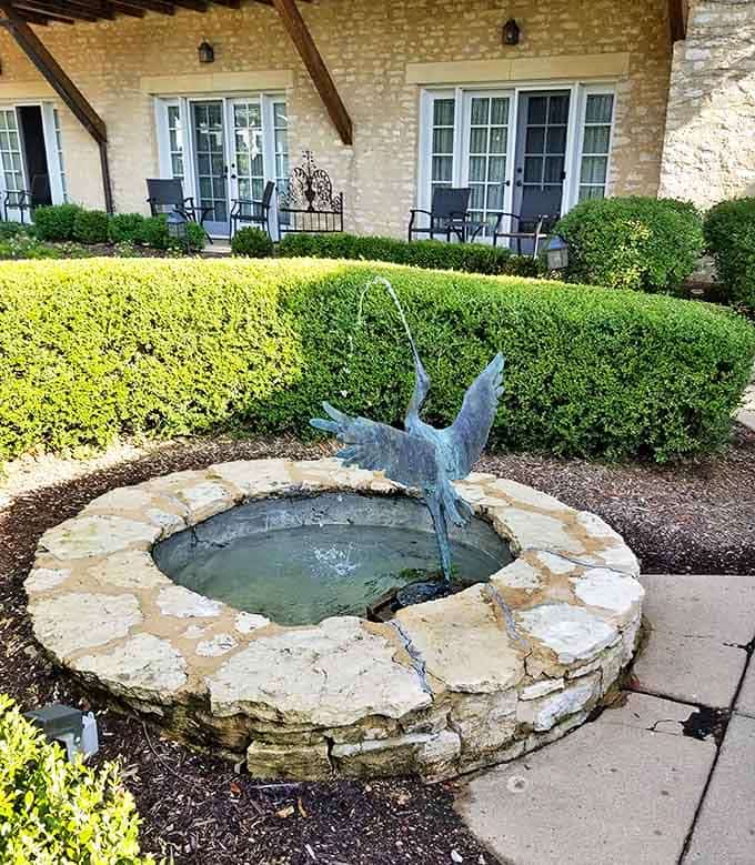 A graceful heron sculpture takes flight from a circular stone fountain, adding gentle bubbling sounds to the property's natural symphony.