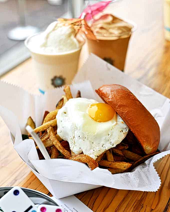 The dynamic duo that launched a thousand cravings: a perfectly crafted burger topped with crispy fries alongside a tropical milkshake.