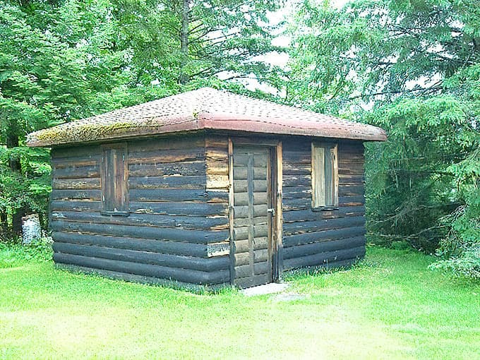 The historic log cabin stands as a humble counterpoint to the garden's artistic ambitions, reminding visitors of the simple lake life that inspired this extraordinary creation.