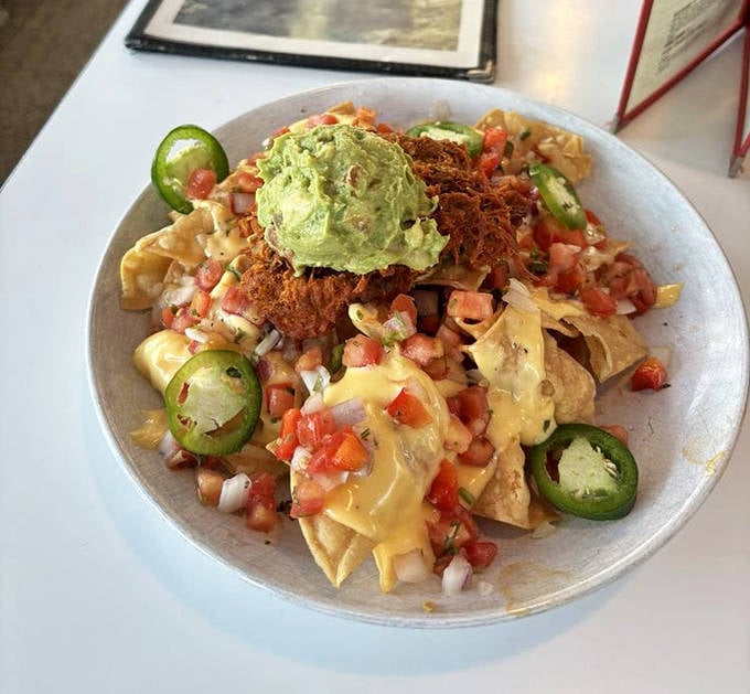 Architecture in food form – layers of chips, cheese, pork, and toppings creating a precarious tower that's worth the inevitable mess.