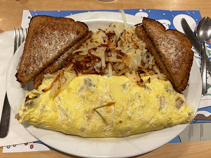 Breakfast perfection on a plate: a cheese-laden omelet nestled beside golden hash browns with perfectly buttered toast for dipping.