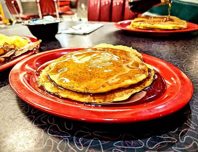 Golden pancakes stacked high enough to require architectural planning, perfect for soaking up lakes of syrup.