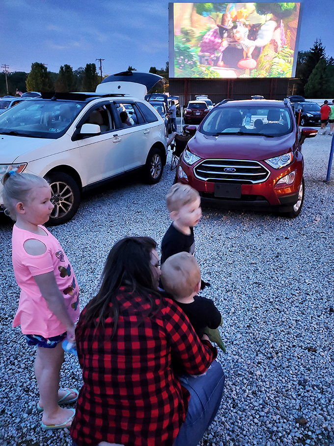 Families create their own viewing spaces between cars, proving the best theater seats might not be seats at all.