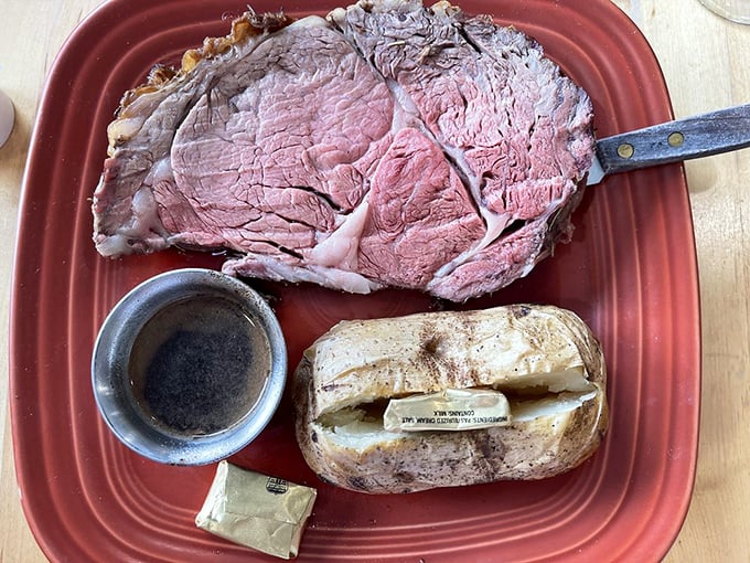 The prime rib special arrives like royalty on its throne of red ceramic, accompanied by a baked potato that's practically begging for butter.