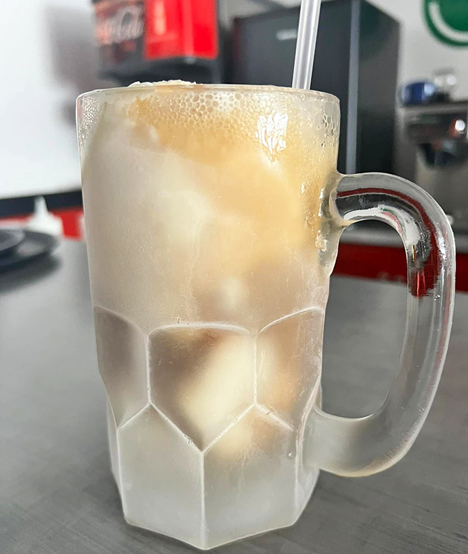 The root beer float arrives in a frosted mug, creating that magical moment when ice cream and soda perform their delicious dance of transformation.