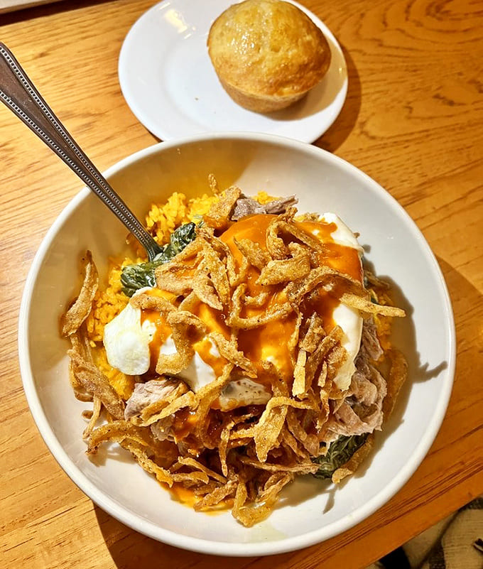 A symphony of textures &ndash; tender pork nestled on yellow rice, topped with crispy onions and a dollop of cooling cream.