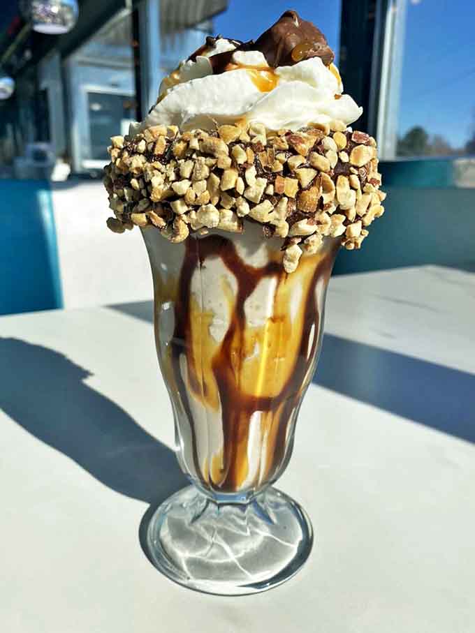 The Snickers shake arrives like a trophy of indulgence, crowned with nuts and caramel that cascade down the sides in sweet, sticky rivulets.