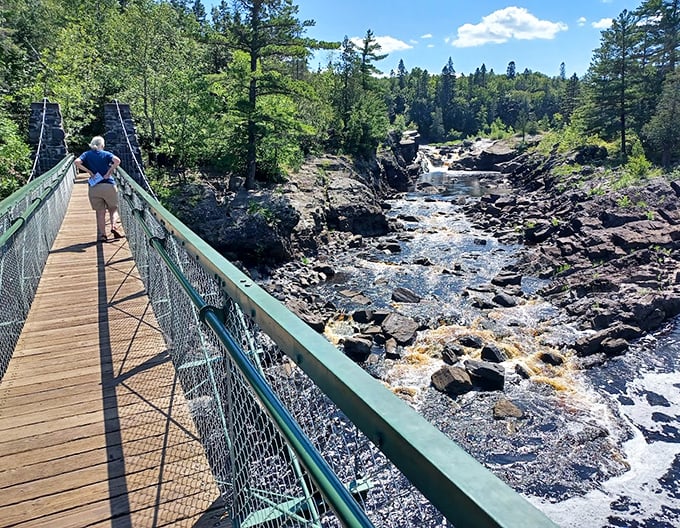 A visitor pauses mid-bridge to take in the spectacular view of rushing waters below.