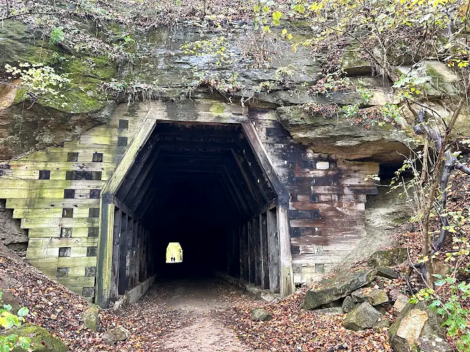 Entrance: Nature frames the tunnel entrance like a portal in a fantasy novel, moss-covered stones telling stories of 19th-century craftsmanship.