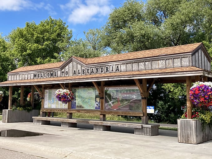 The rustic welcome kiosk, adorned with vibrant hanging baskets, offers visitors their first taste of Alexandria's famous Minnesota hospitality.