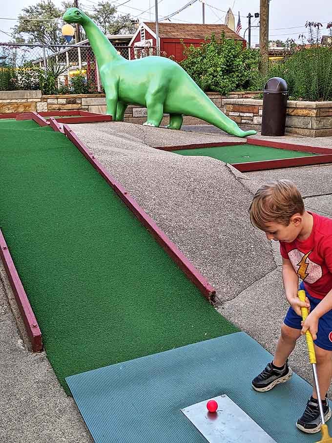 Future golf pro or just enjoying the dinosaur obstacle? Either way, childhood memories are being crafted one colorful putt at a time.