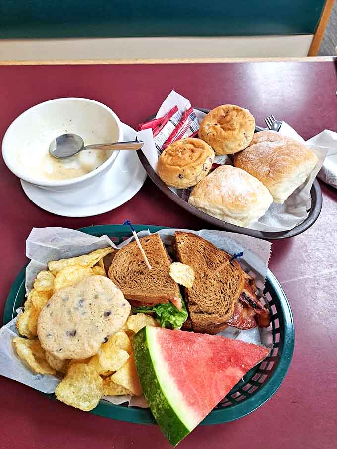 Lunch perfection: a hearty sandwich served with chips, fresh watermelon, and what appears to be soup. Plus a cookie, because why not?
