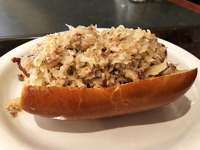 A sandwich that means business: house-made sauerkraut piled high on a bratwurst, nestled in a fresh-baked roll that's both pillow and platform.