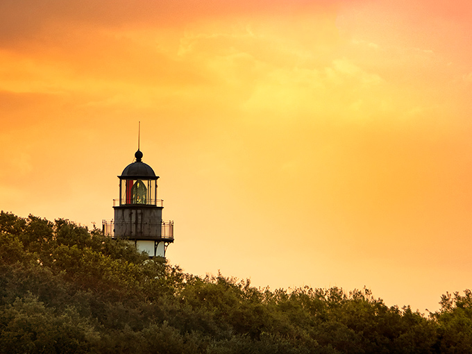 Sunset transforms the lighthouse into a glowing beacon against the amber sky &ndash; nature's spotlight on maritime history.