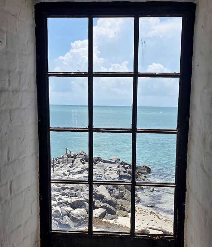 Through this weathered window, lighthouse keepers once watched for ships in peril, framing the Atlantic in a perfect maritime portrait.