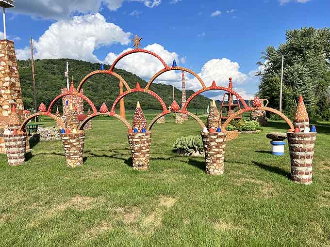 Colorful stone arches create a magical pathway at Prairie Moon Sculpture Garden, their vibrant red tops contrasting with the green landscape.